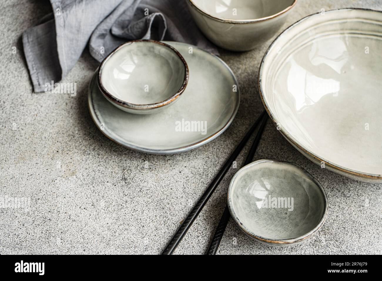 Set of grey ceramic crockery on a concrete background in the same color ...