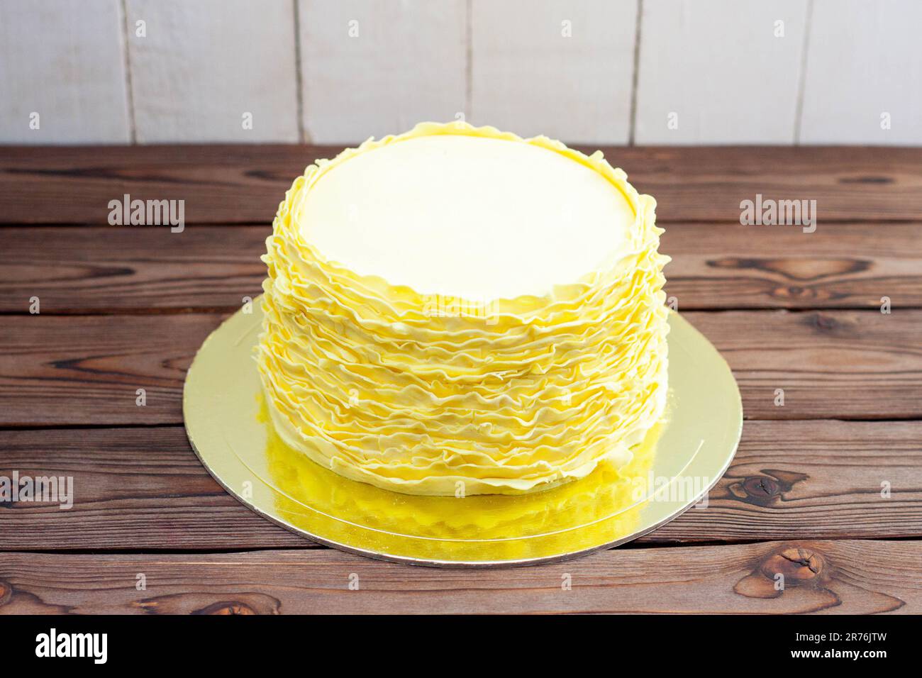 Yellow cake with fondant ruffles on rustic wooden background Stock ...