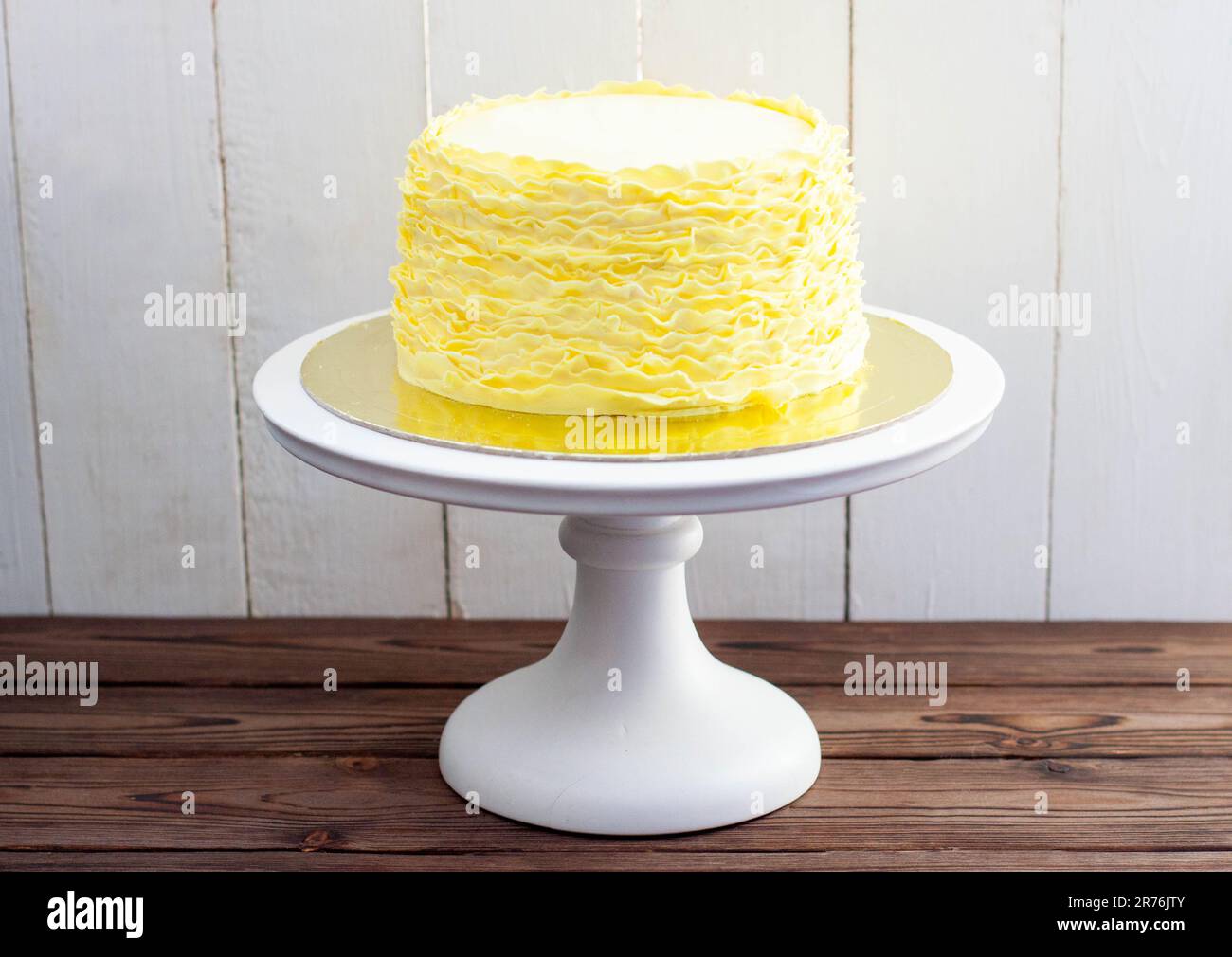 Yellow cake with fondant ruffles on rustic wooden background Stock ...