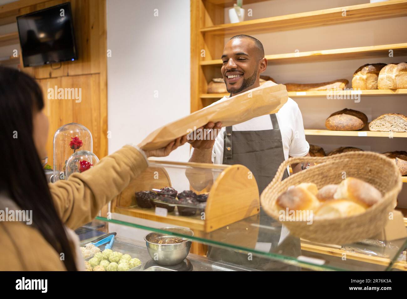 Smiling African American male in bakery shop standing with products in ...