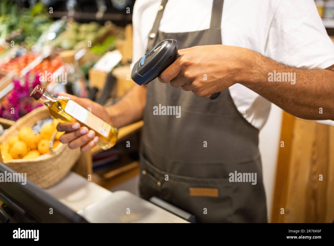 Unrecognizable male seller in apron standing near counter and scanning ...
