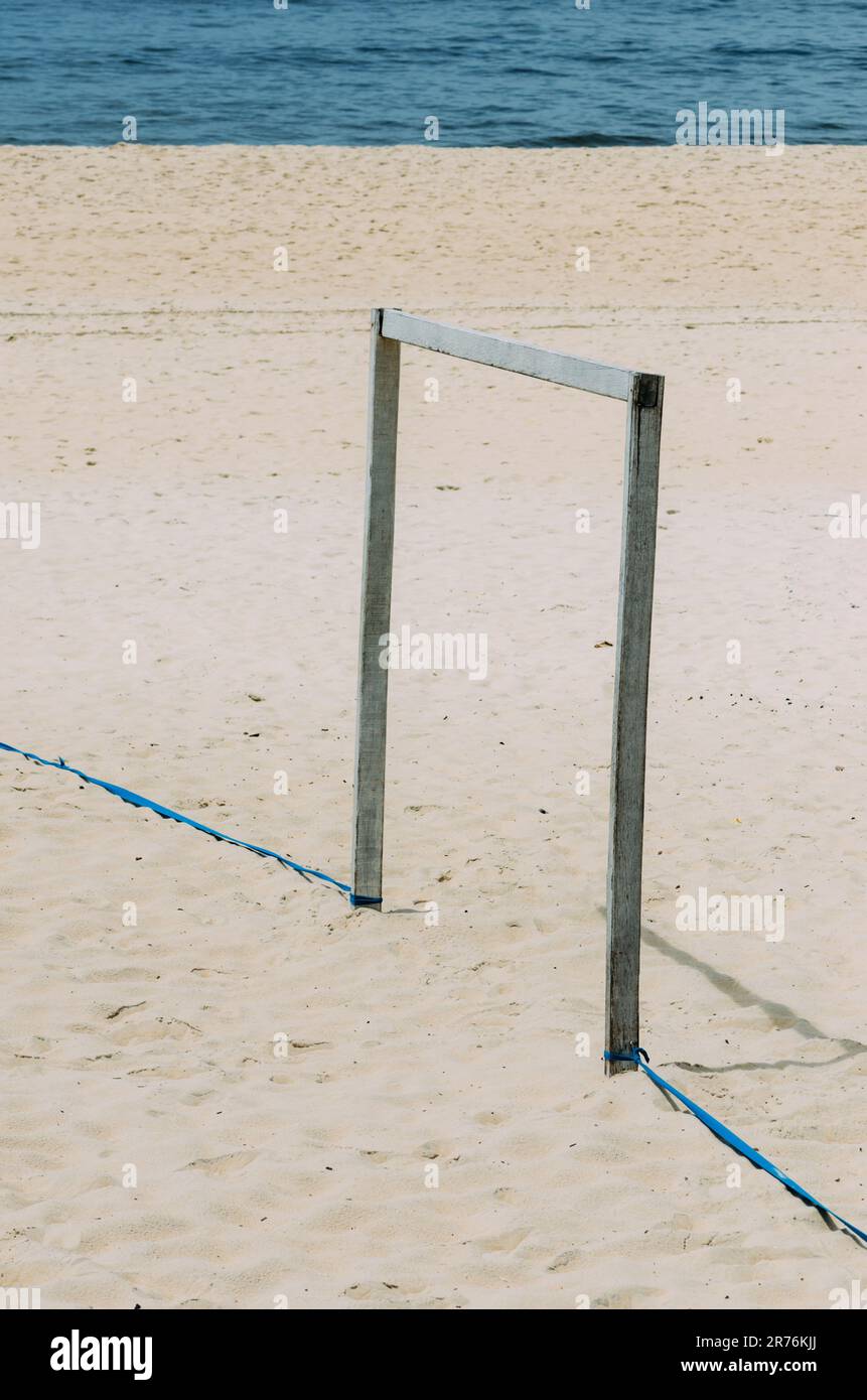 A soccer goal stands atop a sandy beach, with the vast blue ocean ...