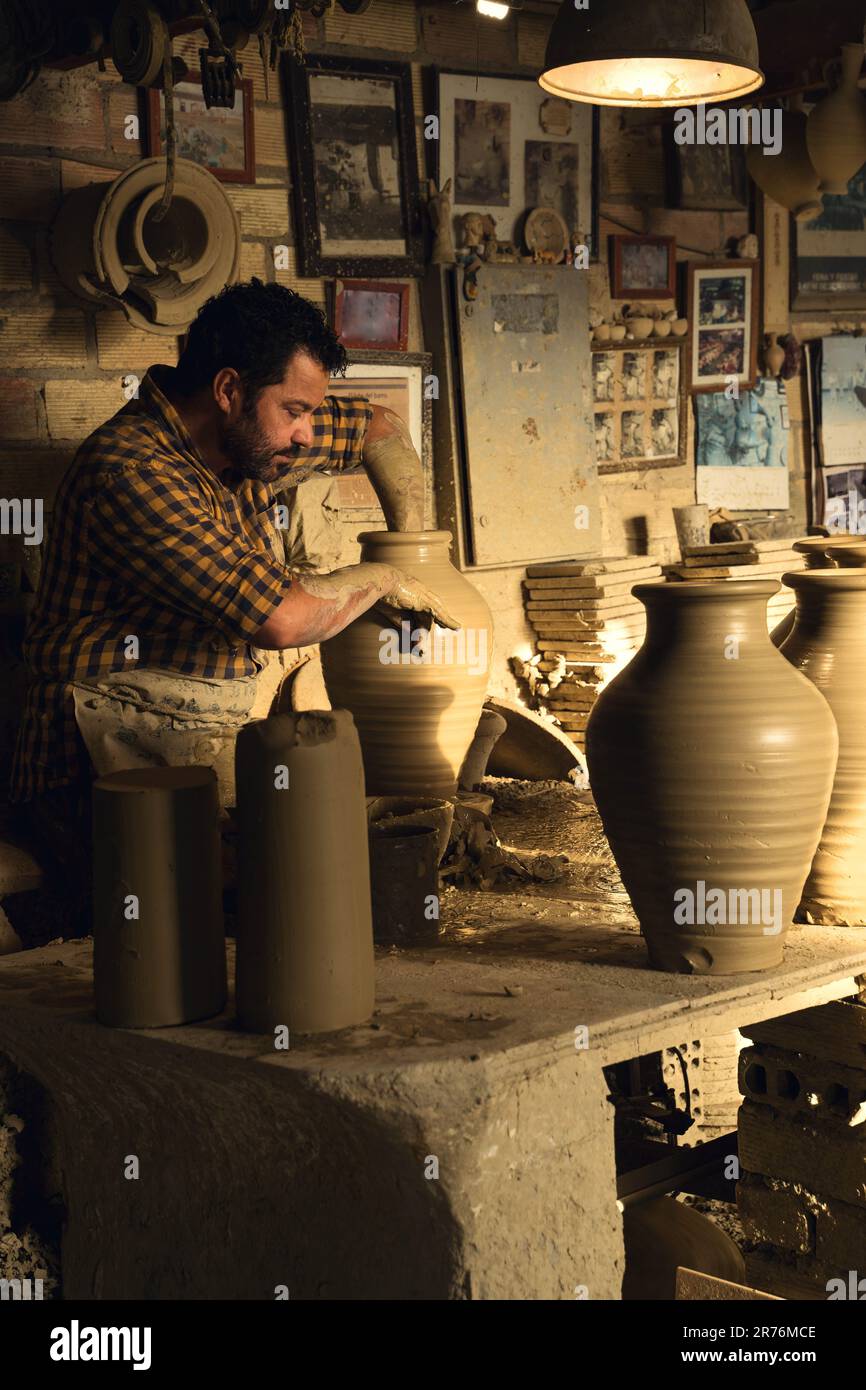 Concentrated adult bearded ethnic male artisan creating clay vase on ...