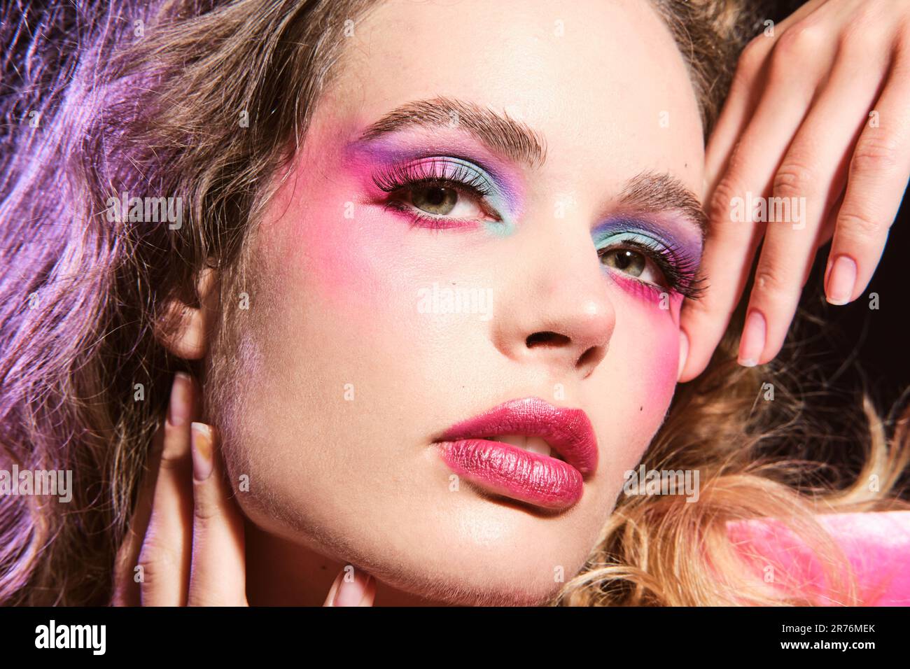 Crop young female model with wavy hair and colorful makeup touching ...