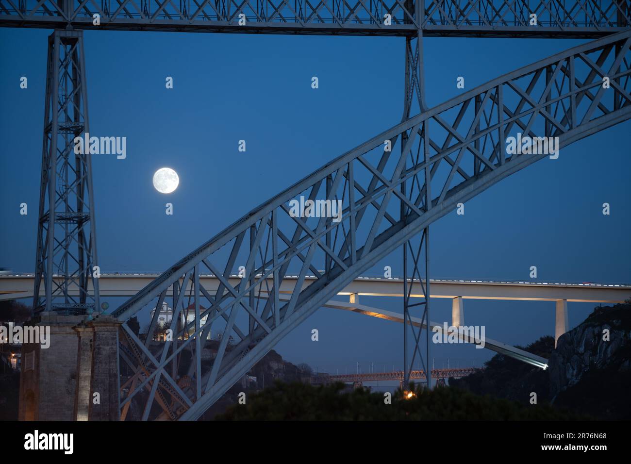 From below of famous bridges located in Porto at night time against bright moon with glowing ...