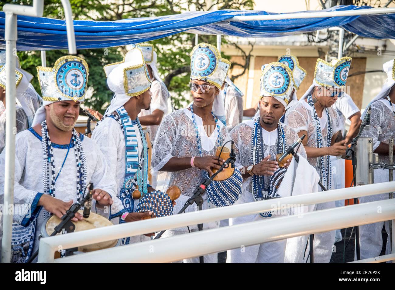A group of people wearing white clothing and playing instruments in ...