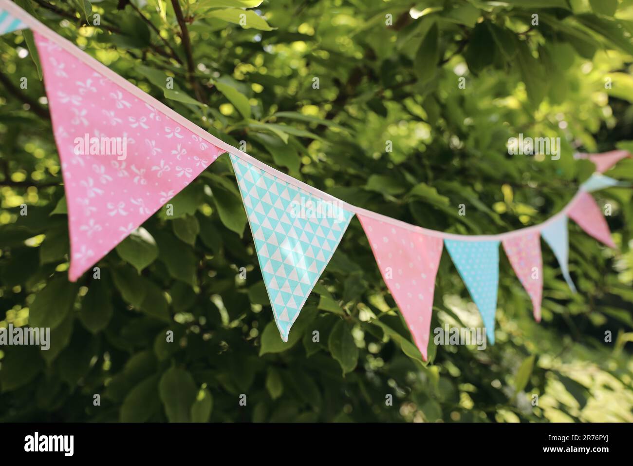 Colorful pink and blue triangular bunting flags hanging among trees ...
