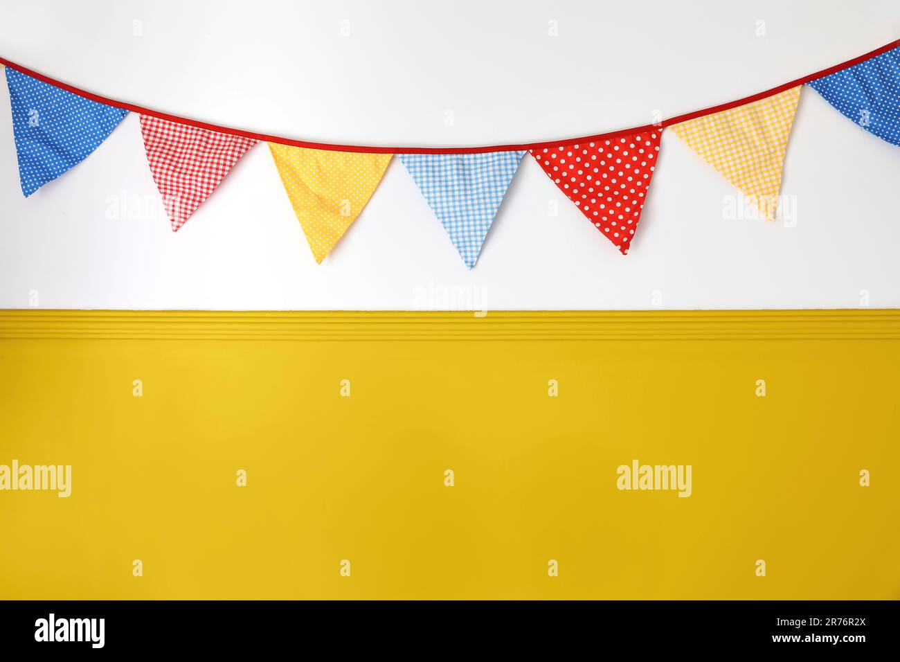 Hanging colorful bunting flags on white wall background. Yellow festive ...