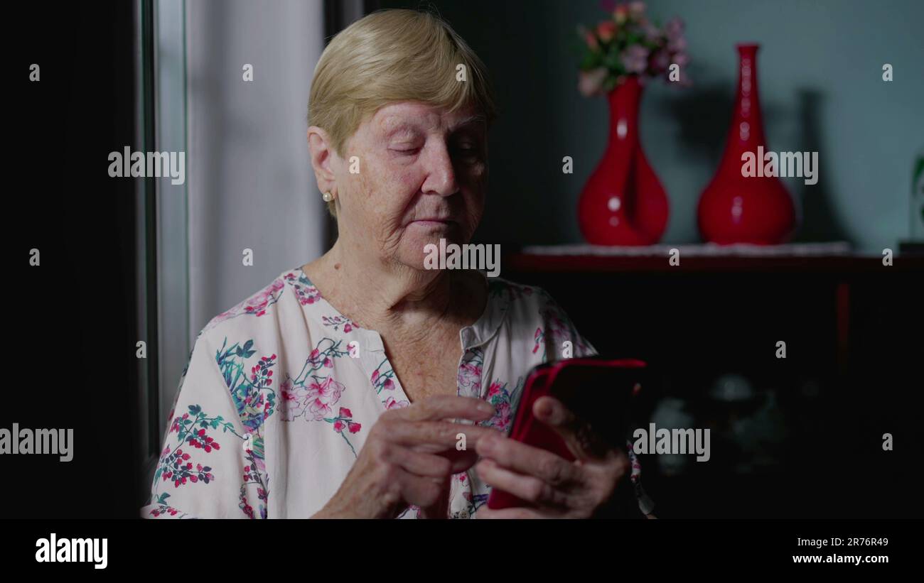 Elderly Woman Scrolling Internet on Phone by Window, Depicting Modern ...