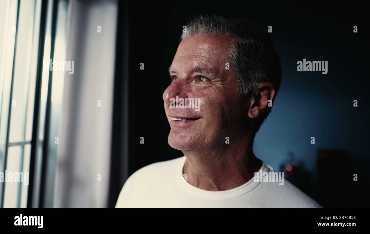 Happy middle-aged older man smiling while gazing out home window Stock ...