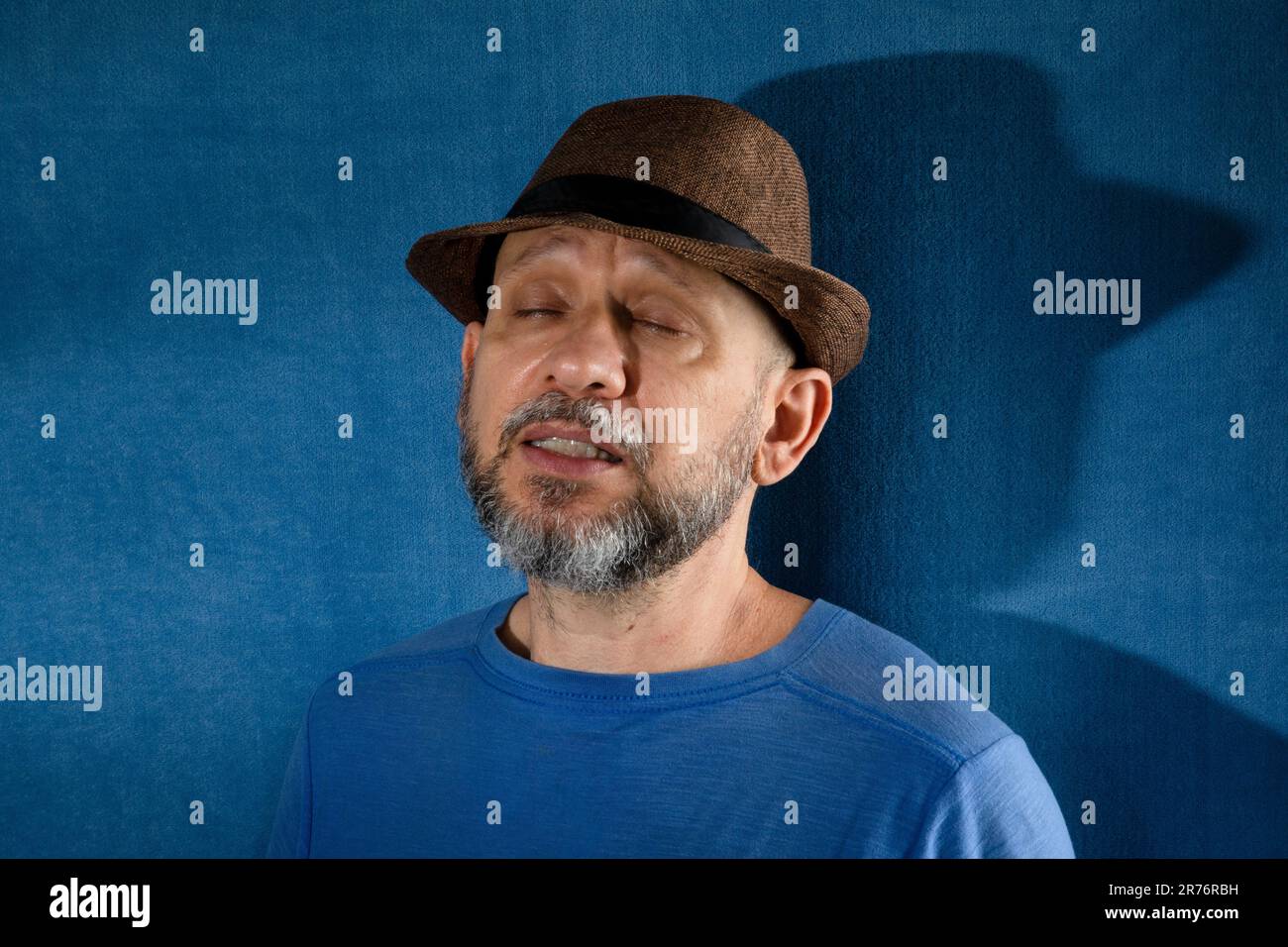 A young adult male wearing a fashionable fedora hat with a weary look ...