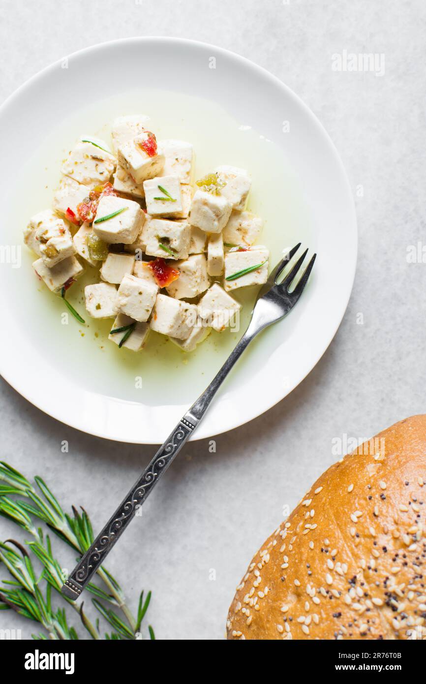 Top view of marinated feta cheese cubes on white plate. Cheese cubes ...