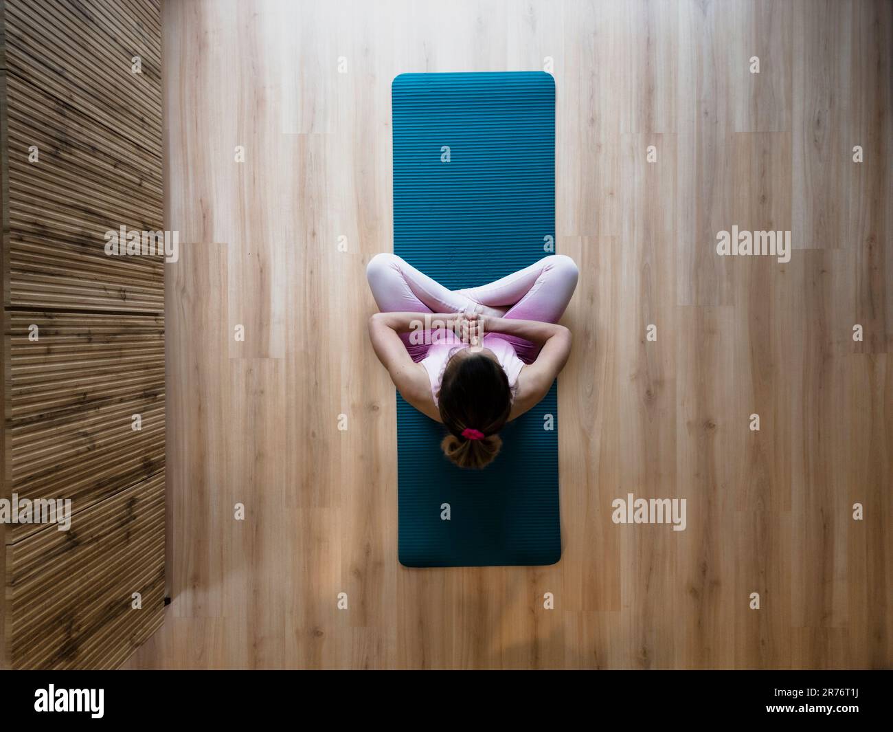 Overhead view of a woman in pink sportswear sitting on an exercise yoga ...