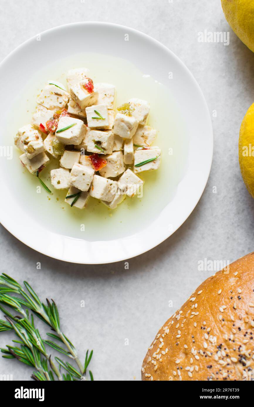 Top view of marinated feta cheese cubes on white plate. Cheese cubes ...