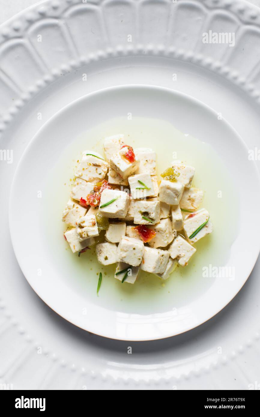 Top view of marinated feta cheese cubes on white plate. Cheese cubes ...