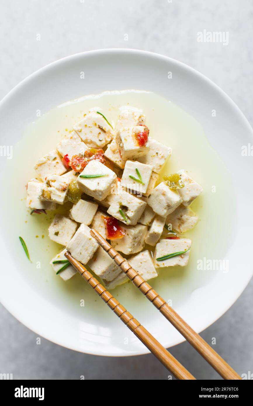Top view of marinated feta cheese cubes on white plate. Cheese cubes ...