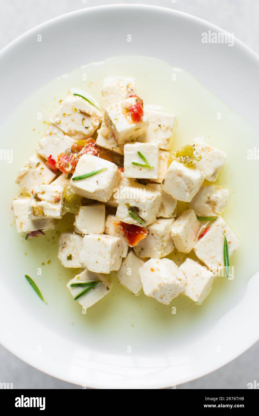 Top view of marinated feta cheese cubes on white plate. Cheese cubes ...