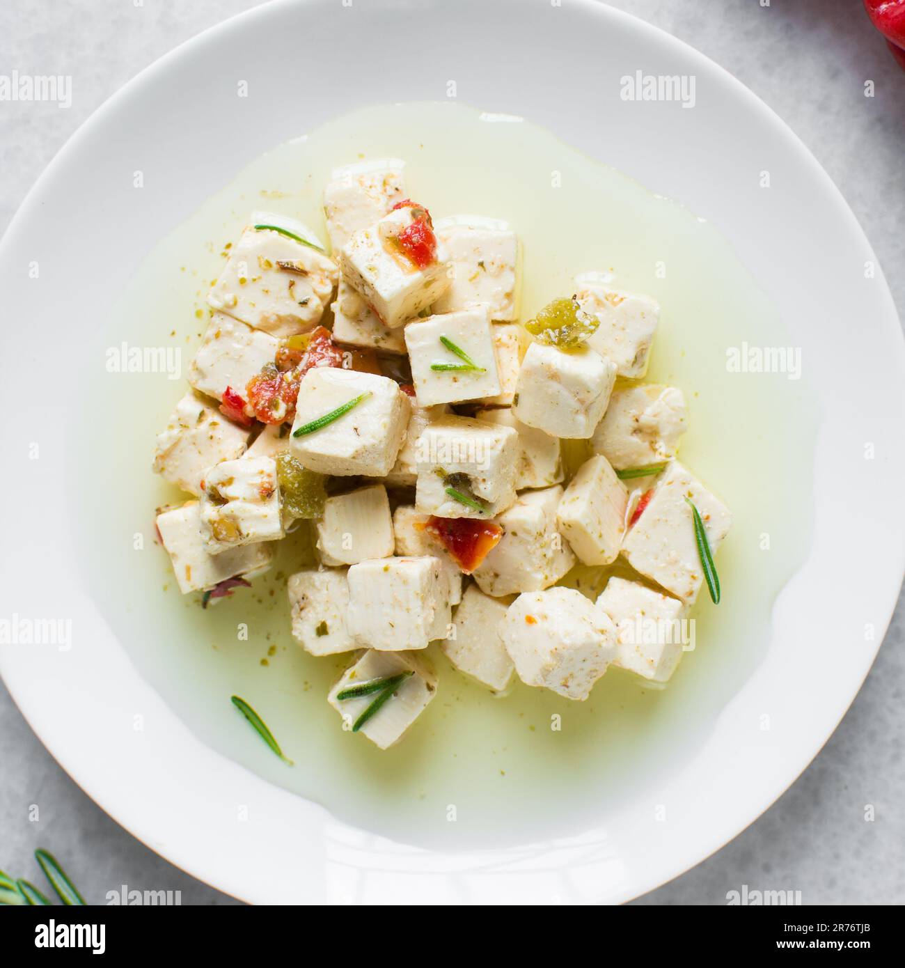 Top view of marinated feta cheese cubes on white plate. Cheese cubes ...