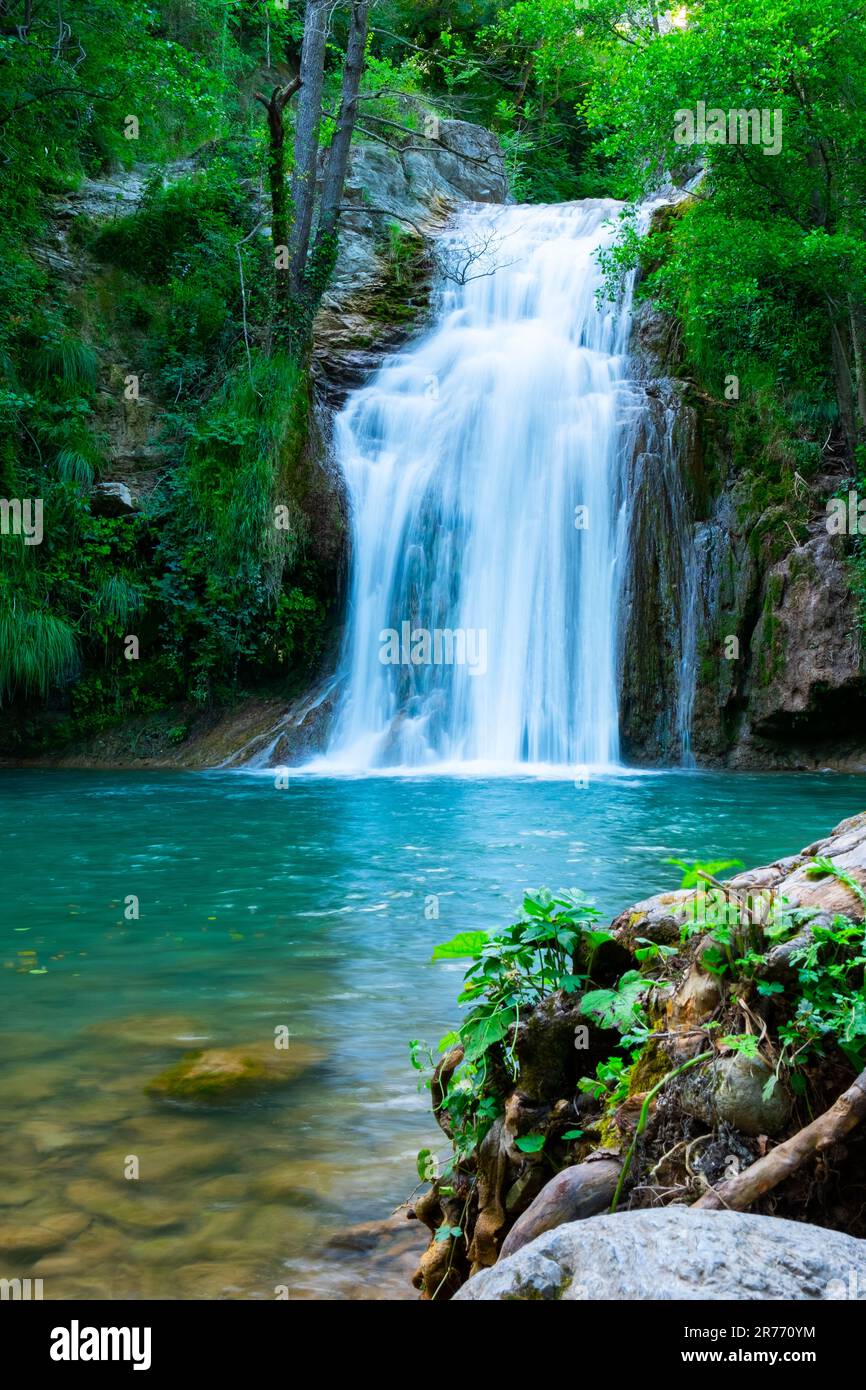 A large beautiful waterfall in a forest with blue water and a trees ...