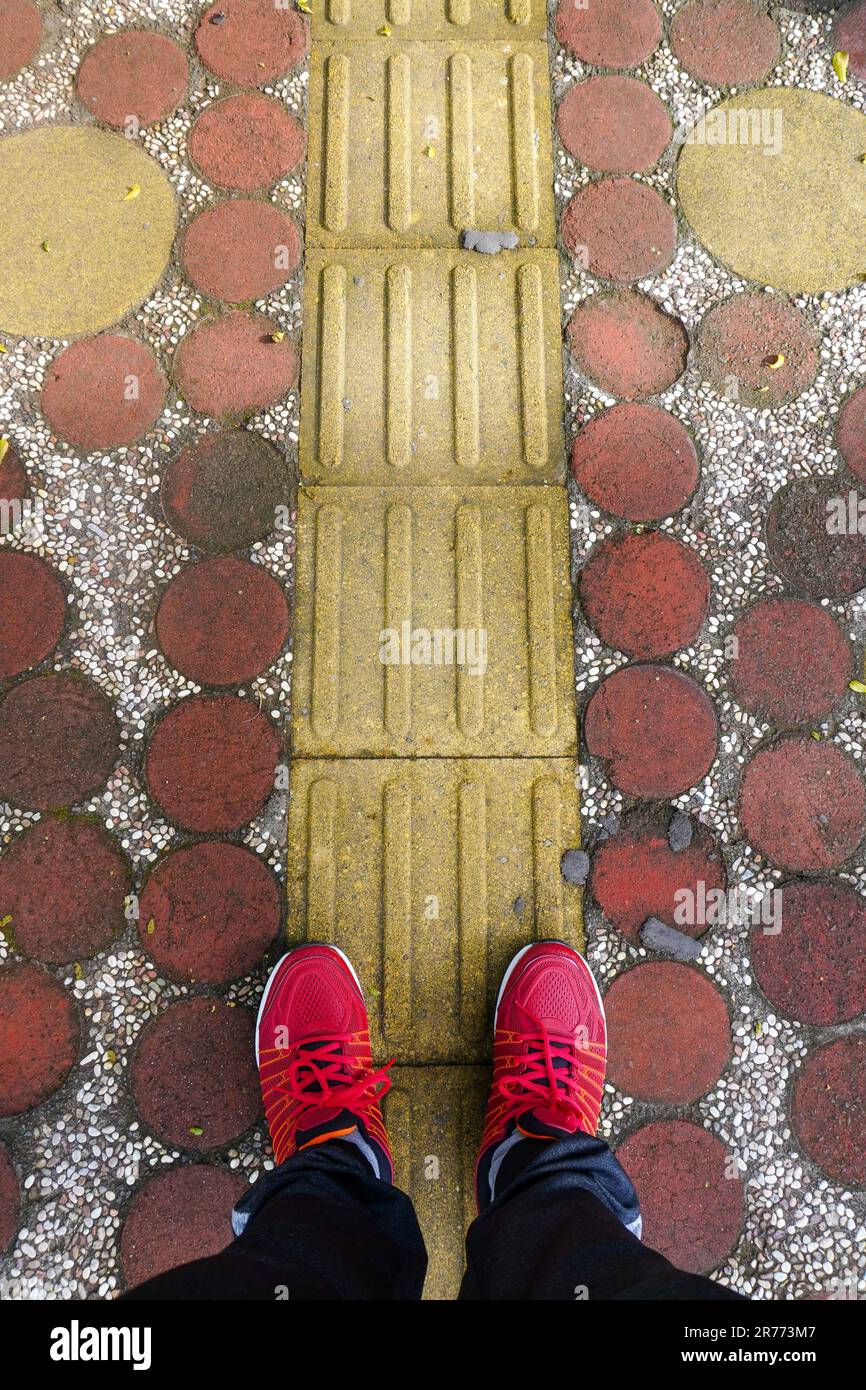 Concept of feet with red shoes on a floor background of colorful bricks ...