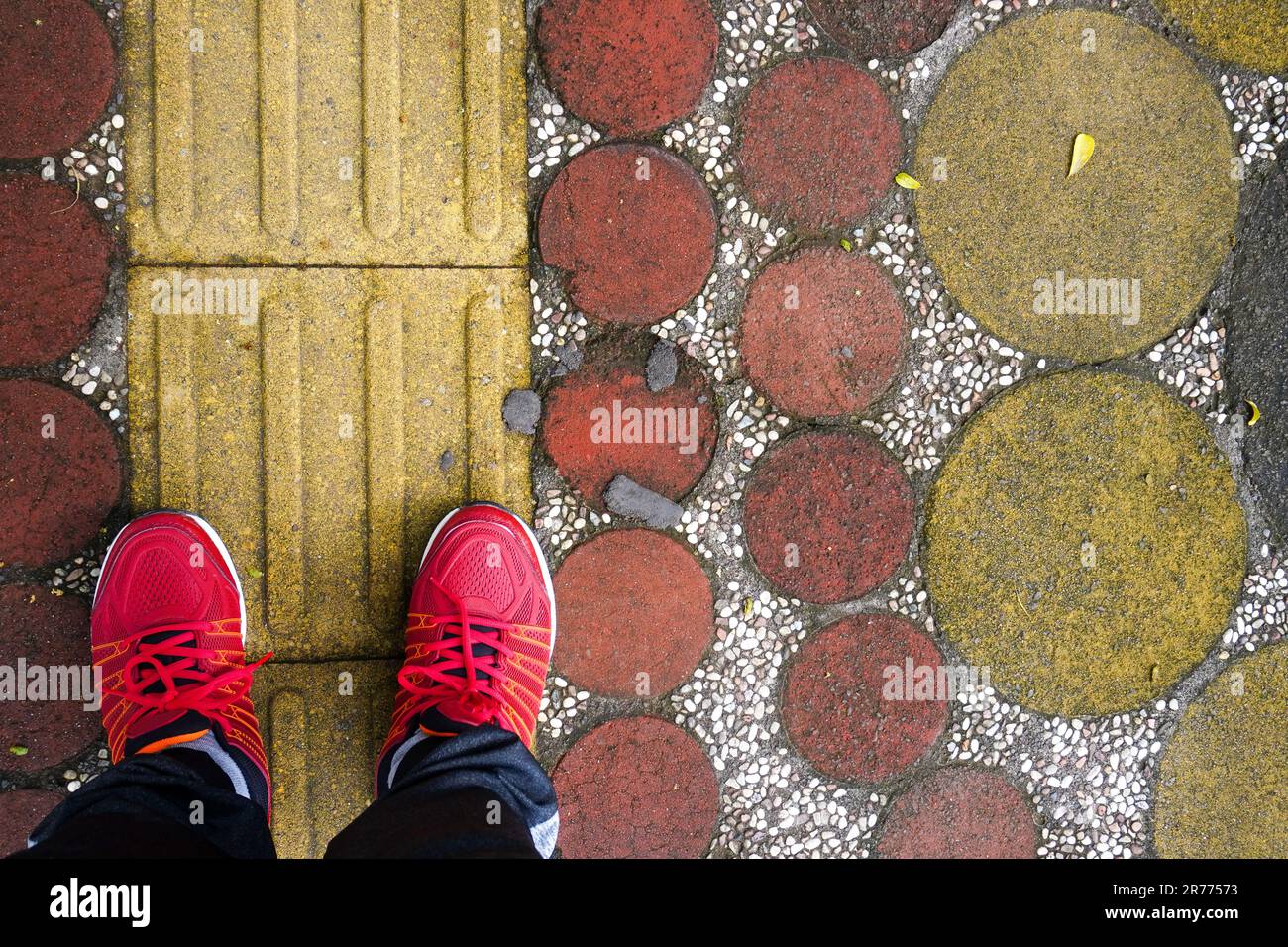 Concept of feet with red shoes on a floor background of colorful bricks ...