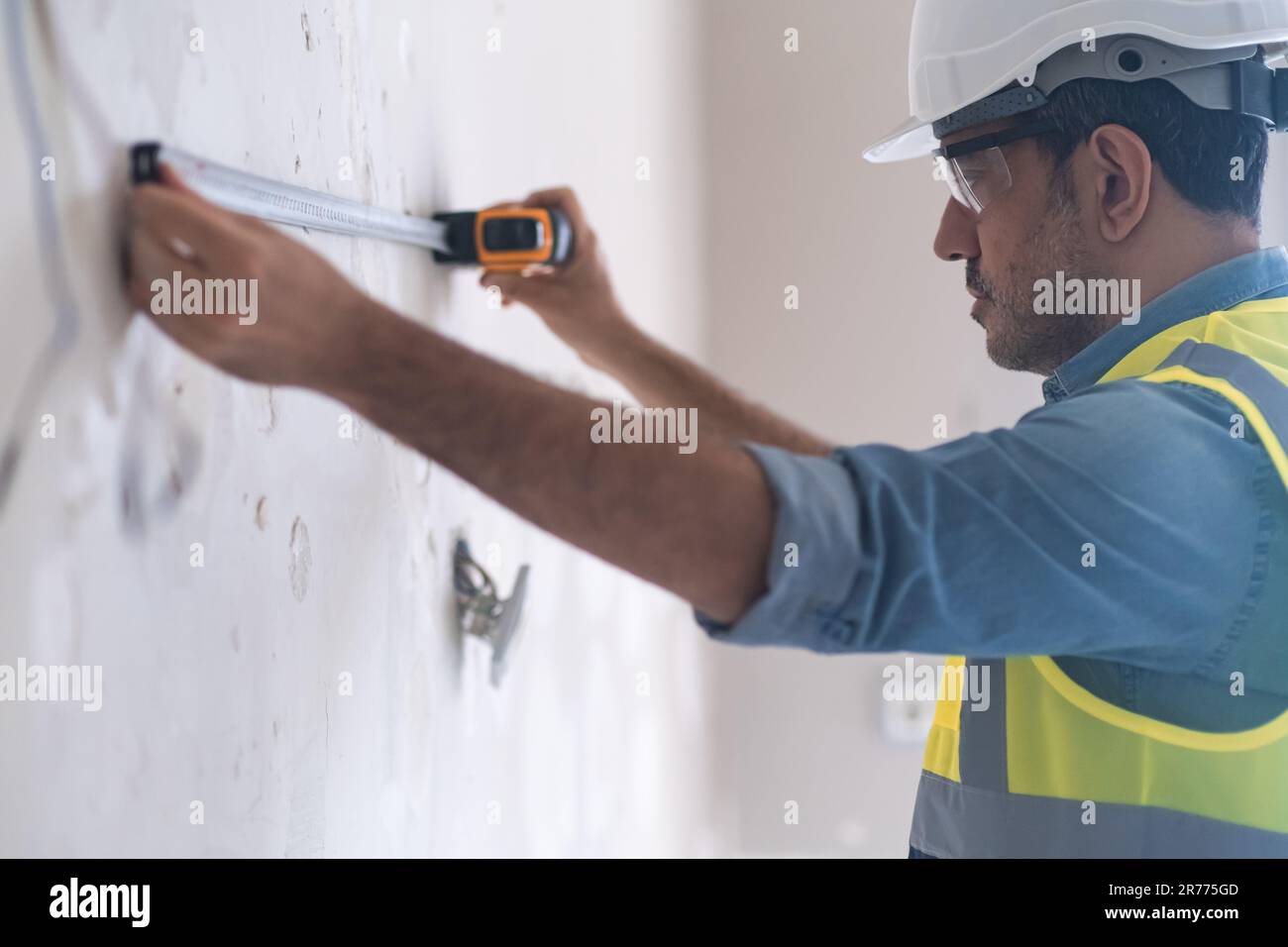 Focused engineer using tape-line to measure distance on wall for socket hole Stock Photo - Alamy