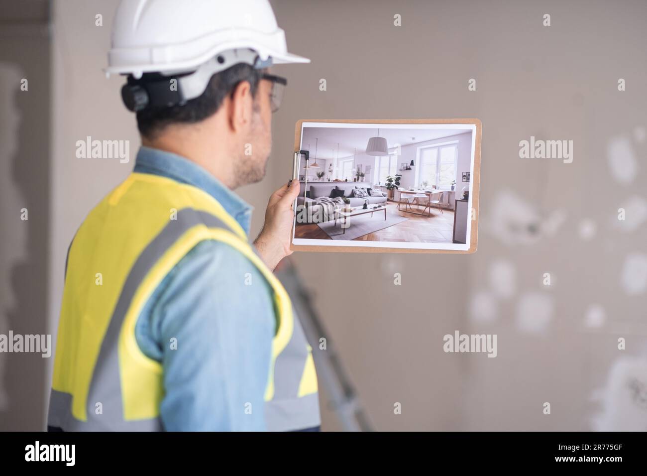 Specialist in white helmet looks at picture with contemporary interior ...
