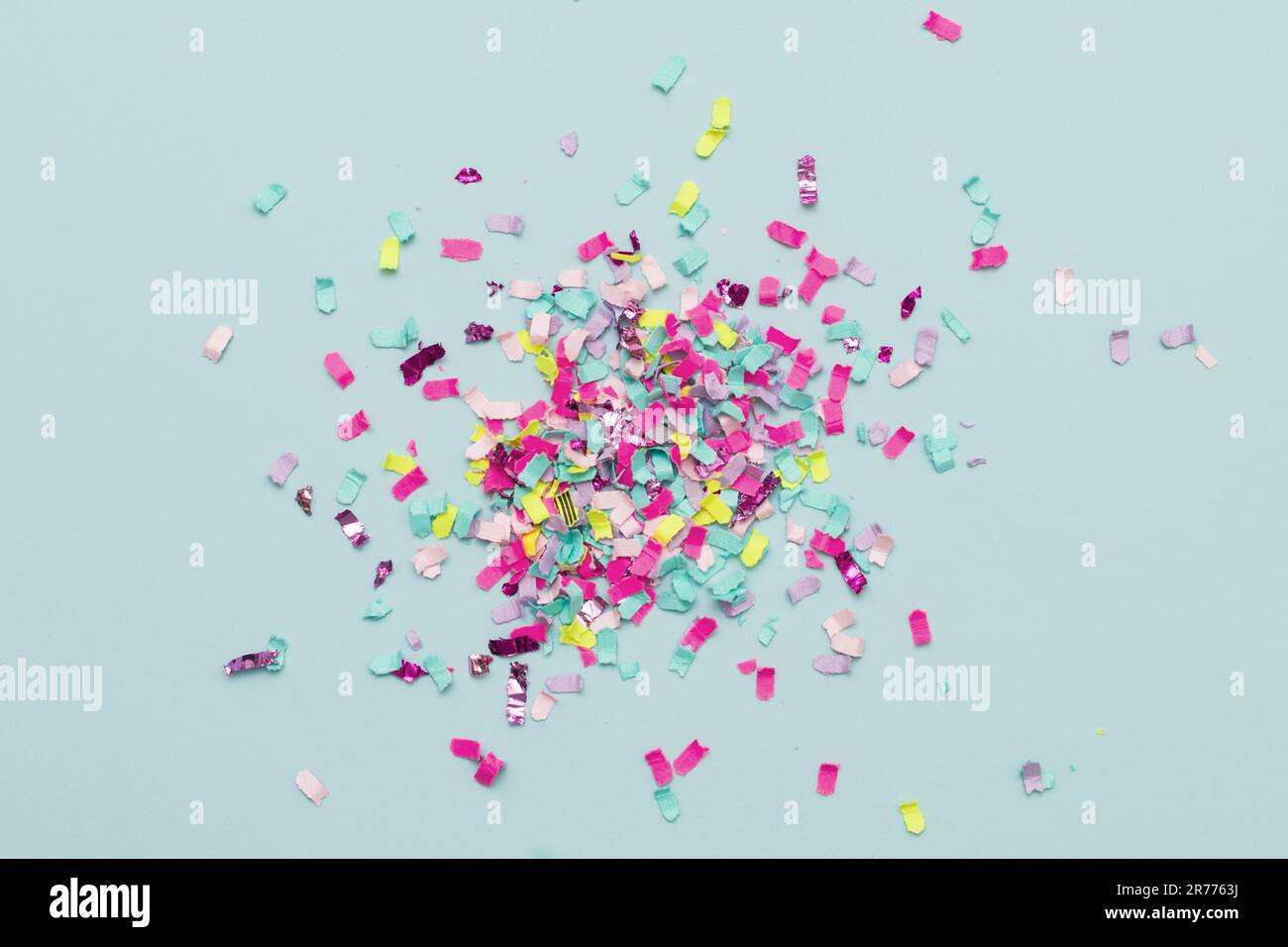 Hot pink, yellow, and colourful sprinkles are scattered on a light blue ...