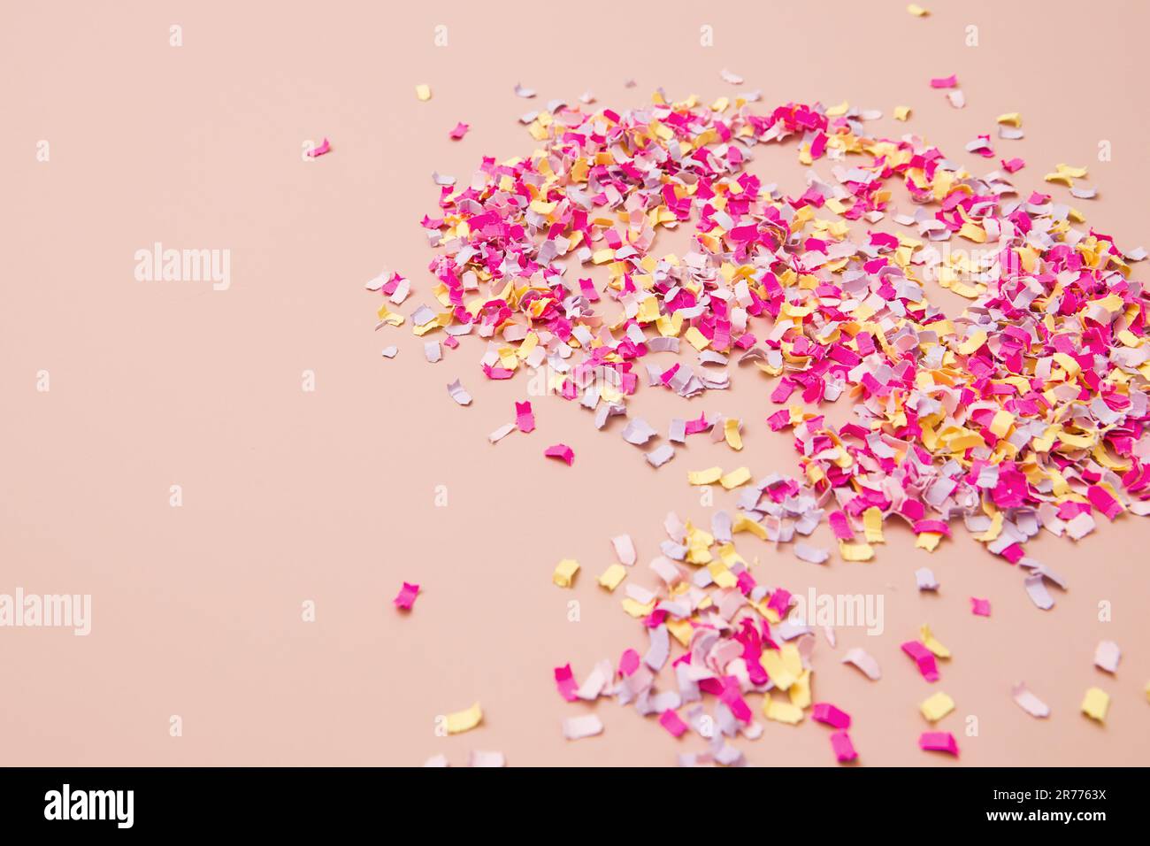 Hot pink, yellow, and colourful sprinkles are scattered on a pink ...