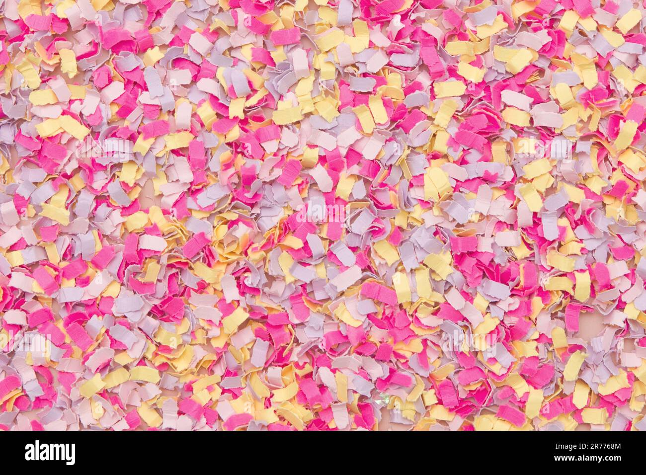Hot pink, yellow, and colourful sprinkles are scattered on a pink ...