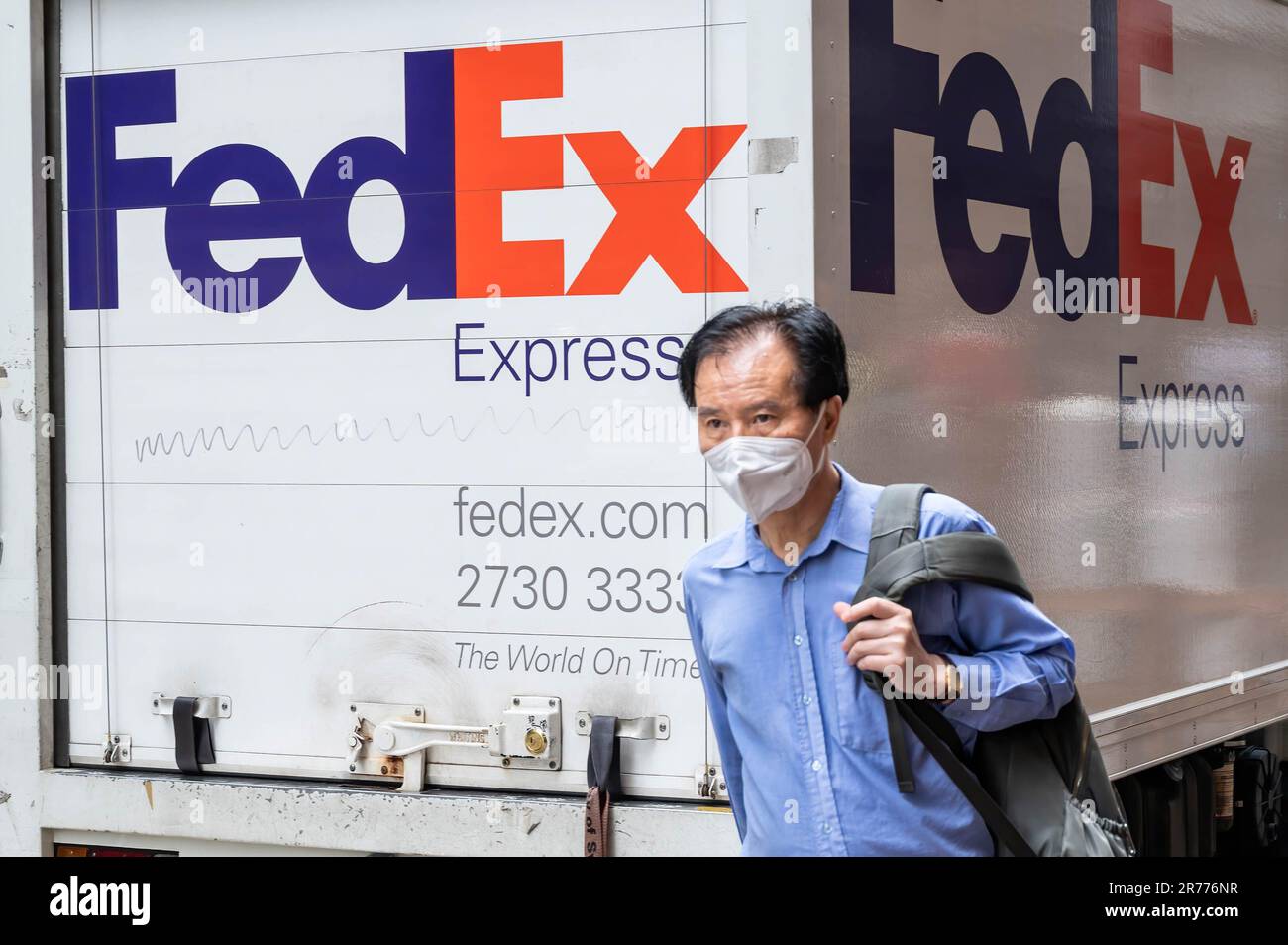 A pedestrian walks past the American FedEx Express delivery truck seen ...