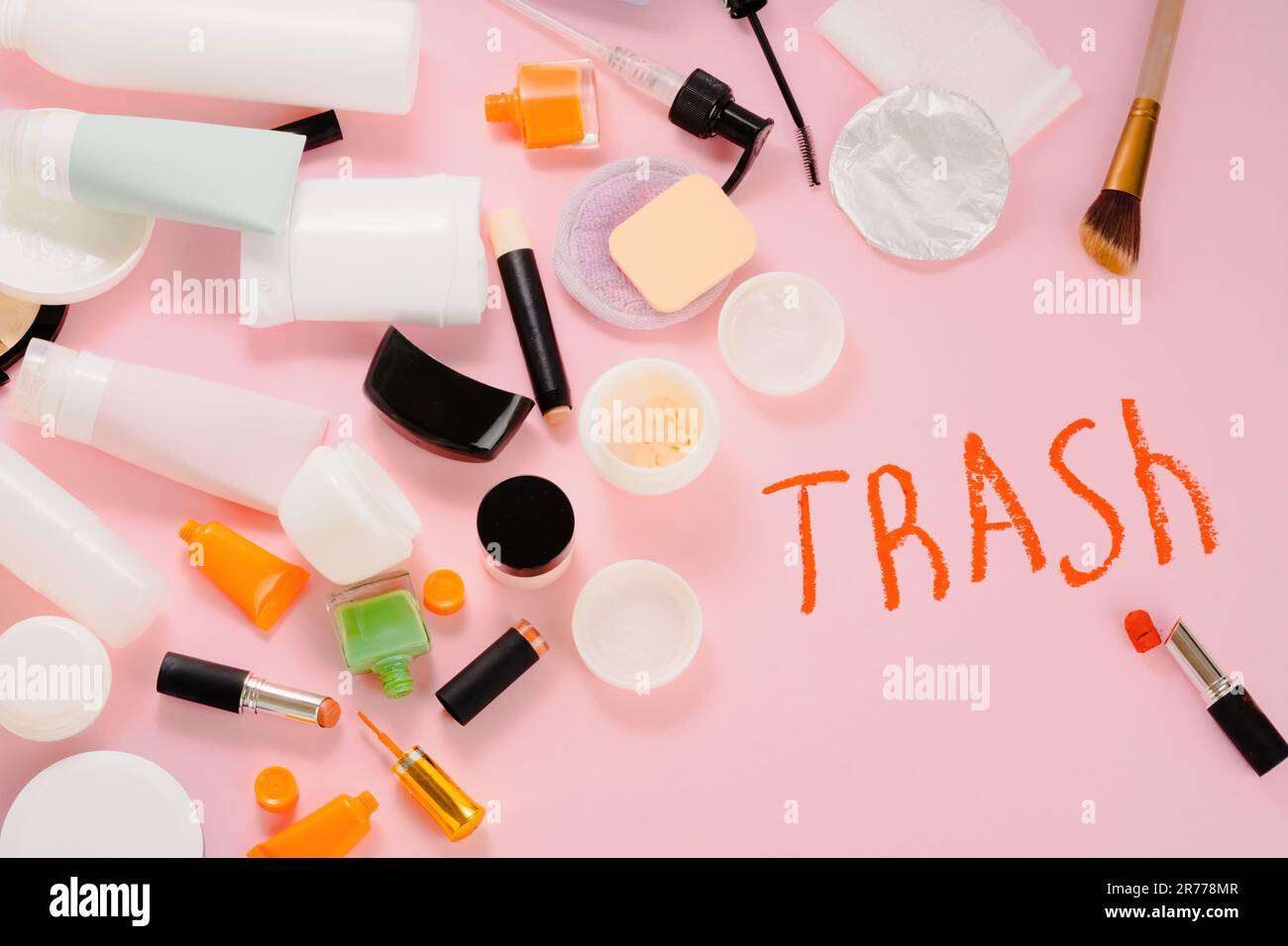 Hand writing with lipstick trash. Beauty packaging products on a pink ...