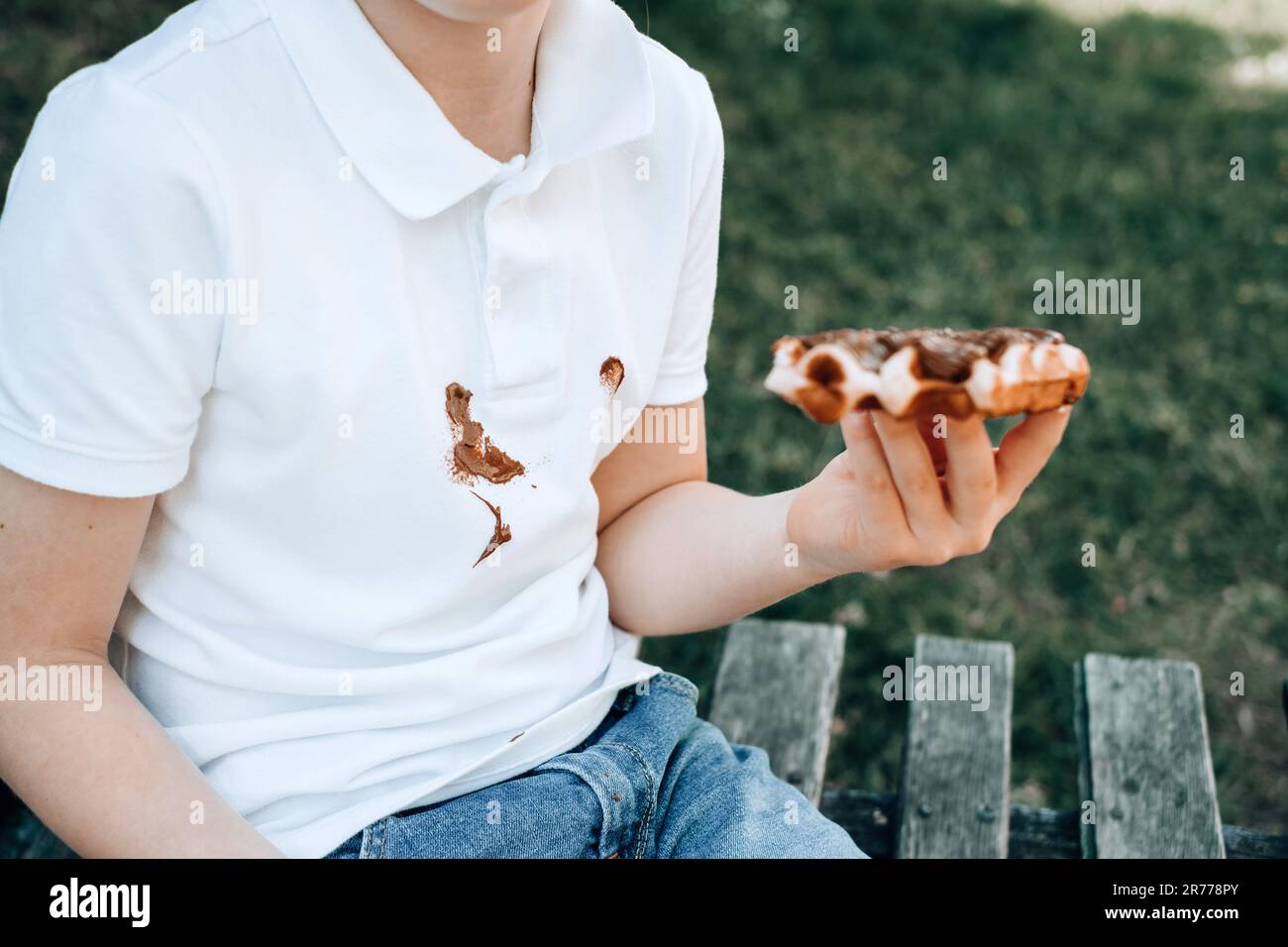 Dirty stain on clothes. A boy eating a sweet pastry covered with ...