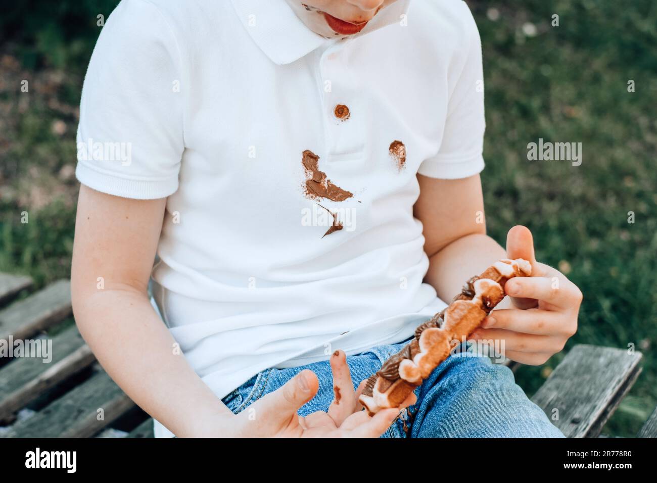 Chocolate stains on white clothes. A boy eating Belgian waffles with ...