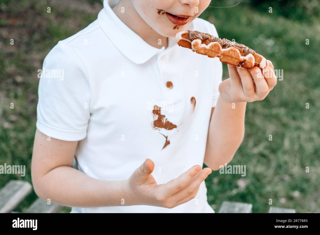 Chocolate stains on white clothes. A boy eating Belgian waffles with ...