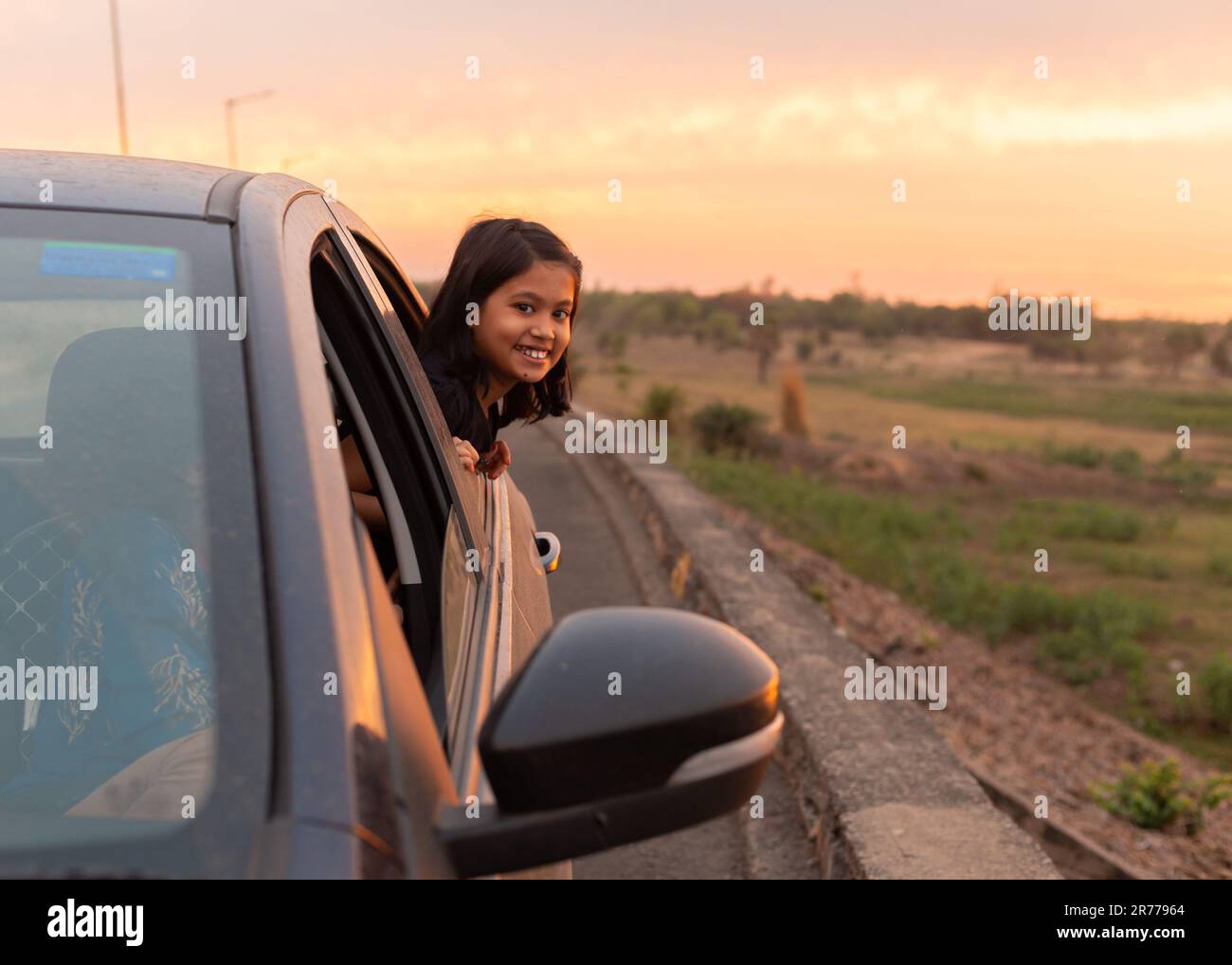 A beautiful young Indian girl child looking out of car window with ...