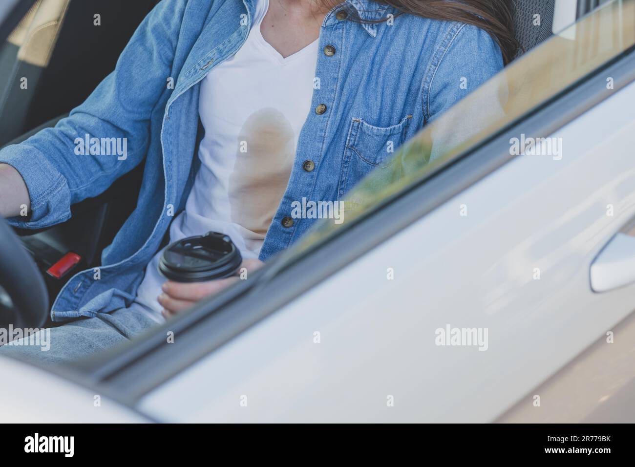 A faceless girl spilling coffee or tea on herself while driving a car ...