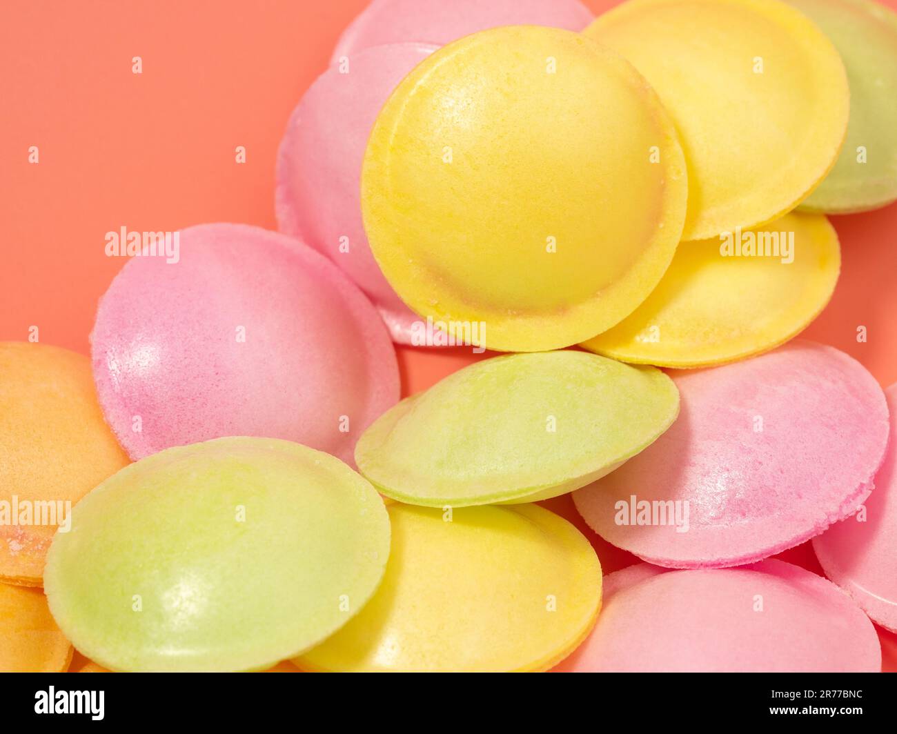 Sweet candies in the shape of a UFO in different colors on a pink ...