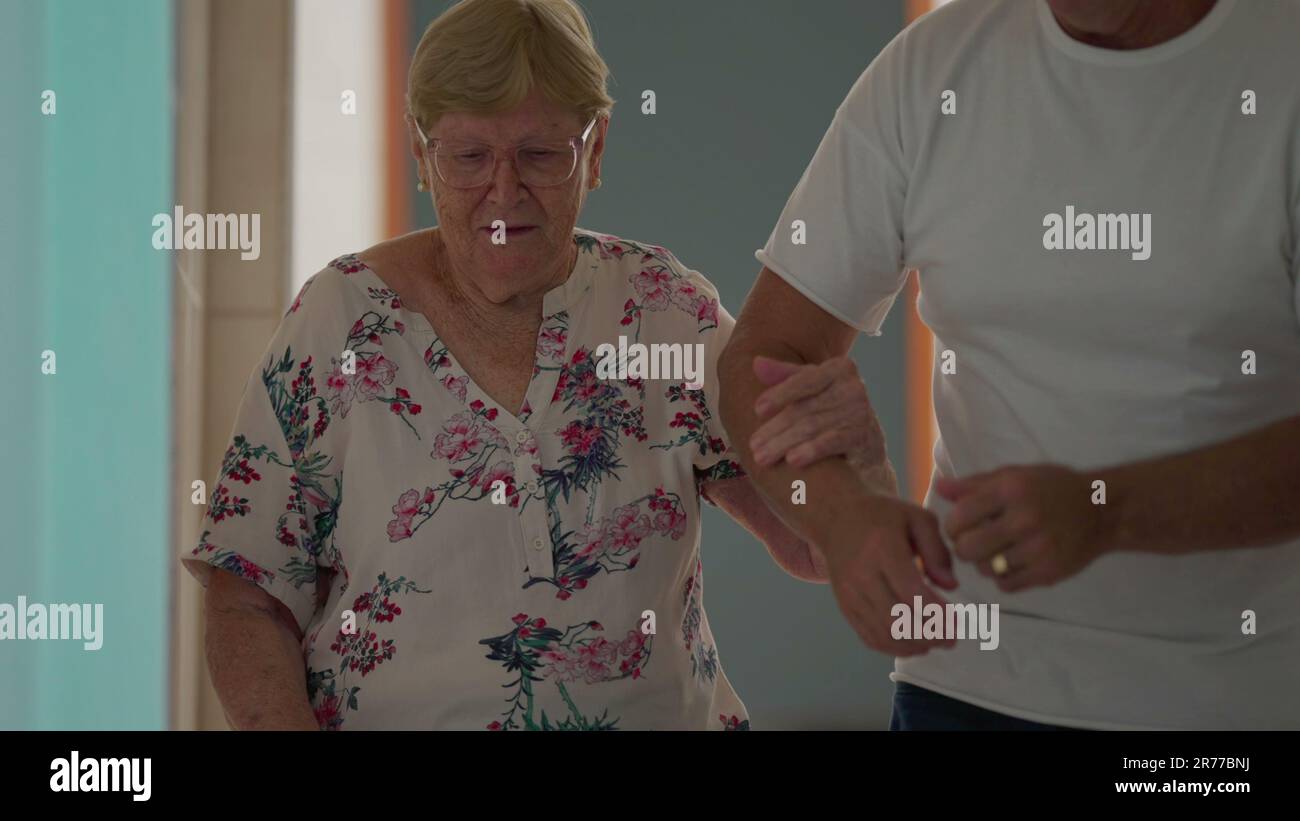 Assisting Elderly woman at home, candid authentic scene of adult son ...