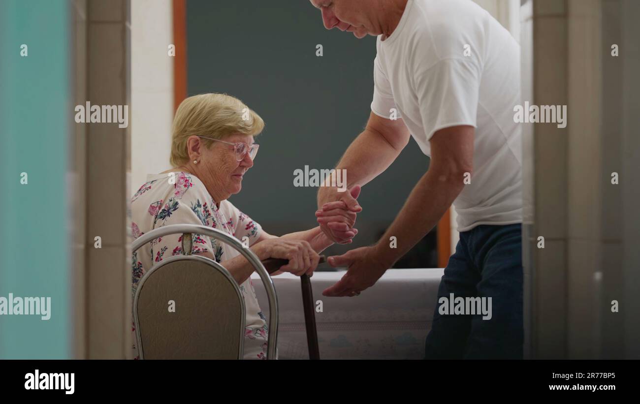 Assisting Elderly woman at home, candid authentic scene of adult son ...