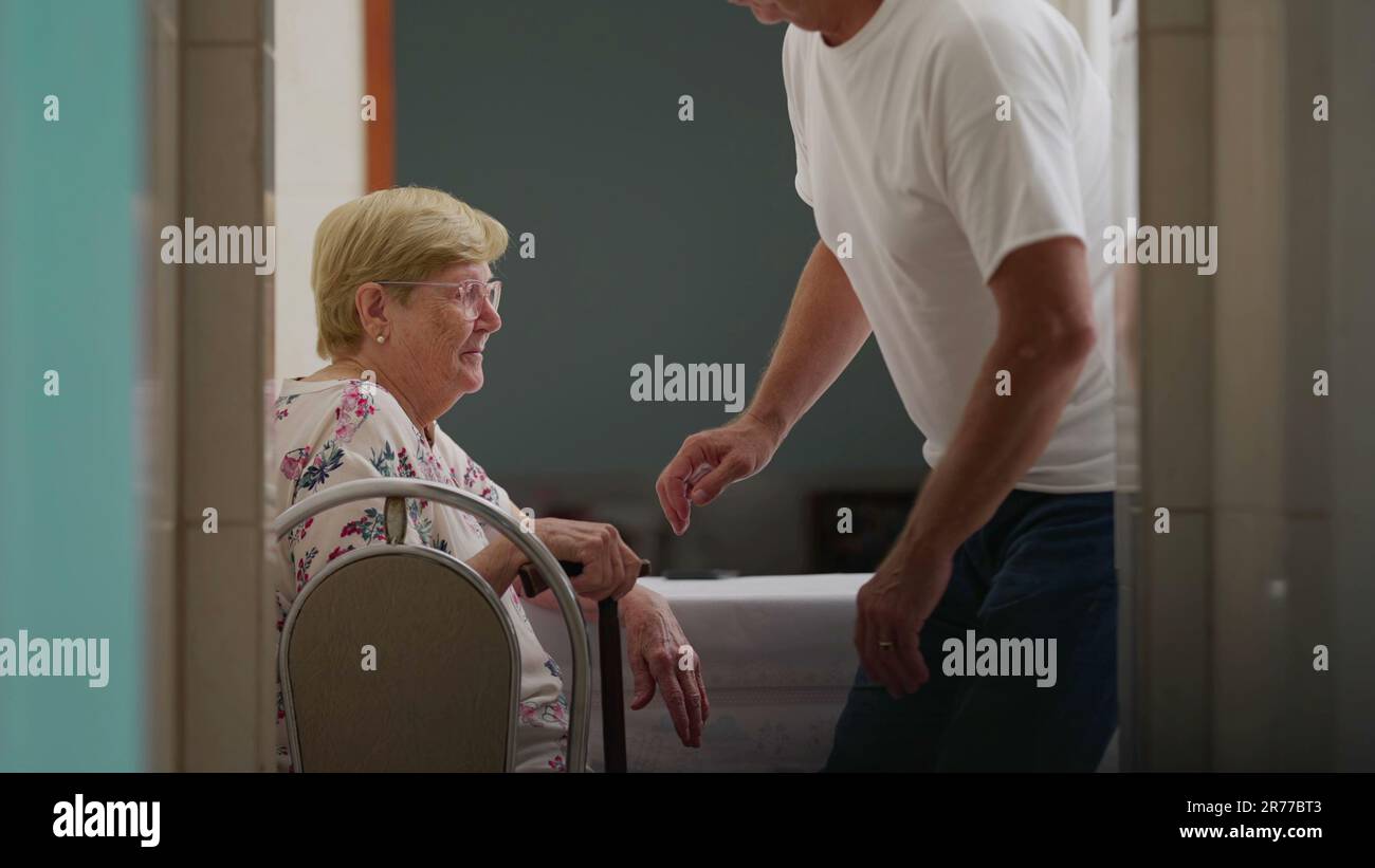 Assisting Elderly woman at home, candid authentic scene of adult son ...