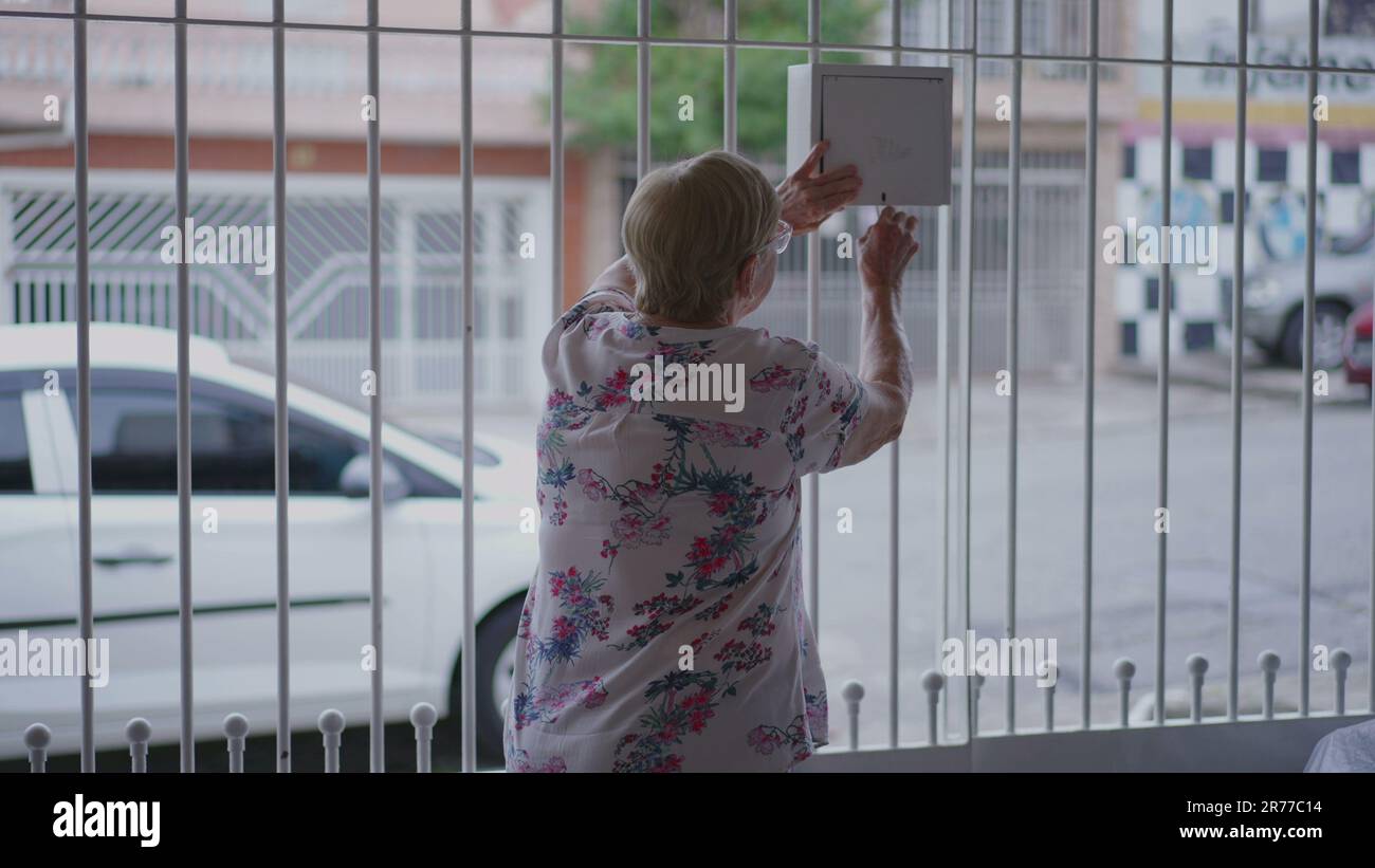 Elderly woman checking mail at front home, senior person opening metal ...