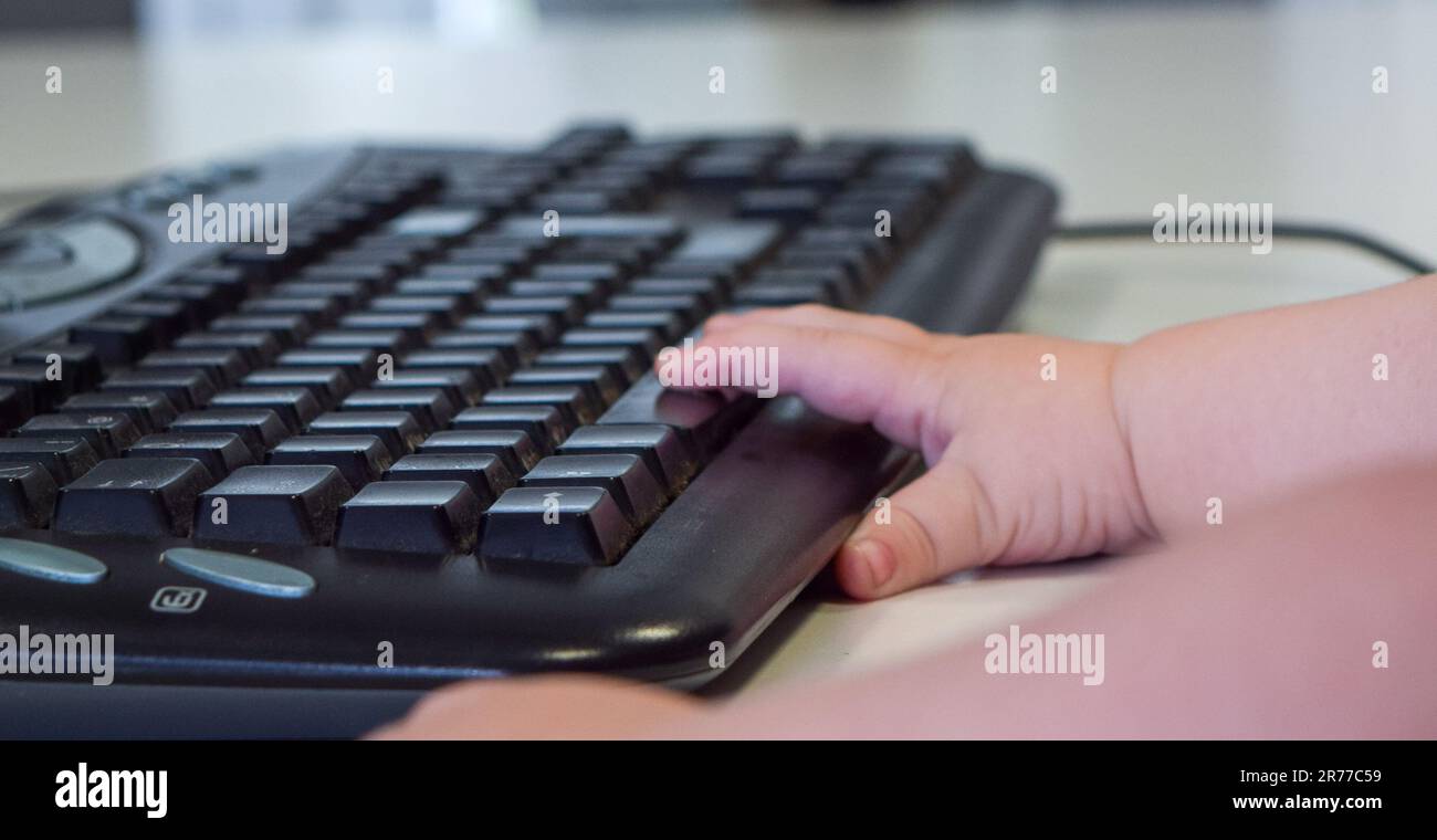 Hand of a baby with the computer keyboard Stock Photo - Alamy
