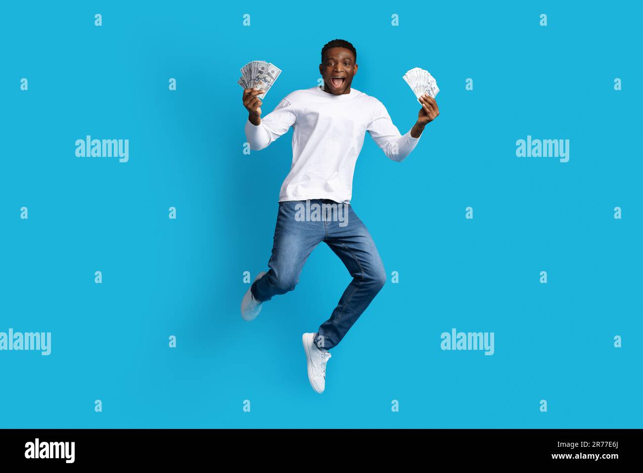 Black guy jumping with money cash in hands, blue background Stock Photo ...