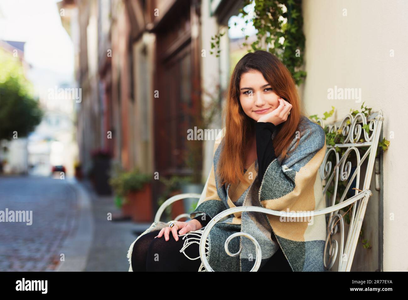 Young fashion 20 year old girl sitting on the bench, wearing warm plaid ...
