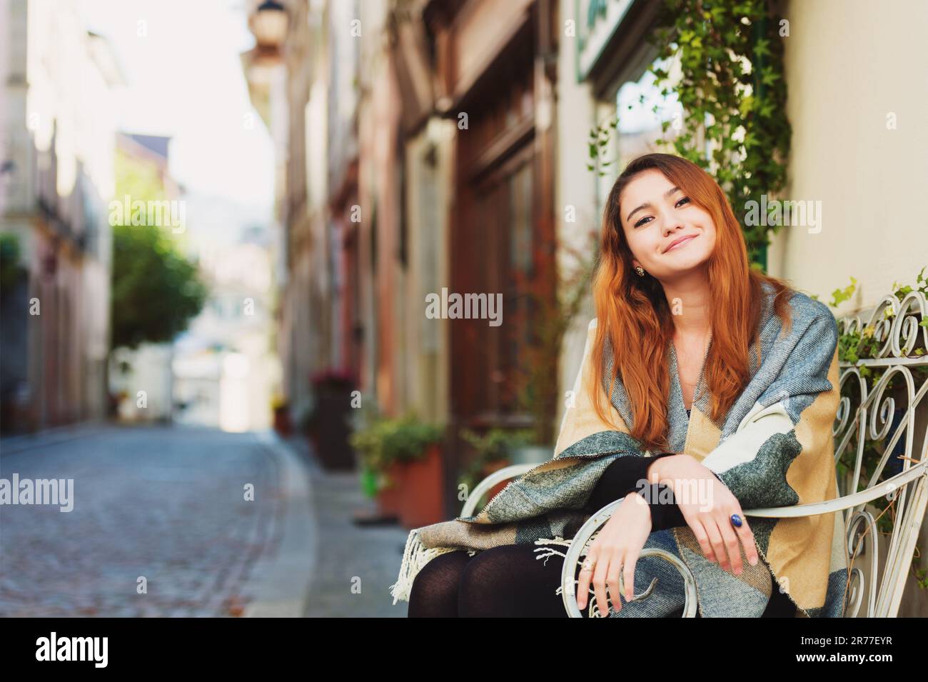 Young fashion 20 year old girl sitting on the bench, wearing warm plaid ...