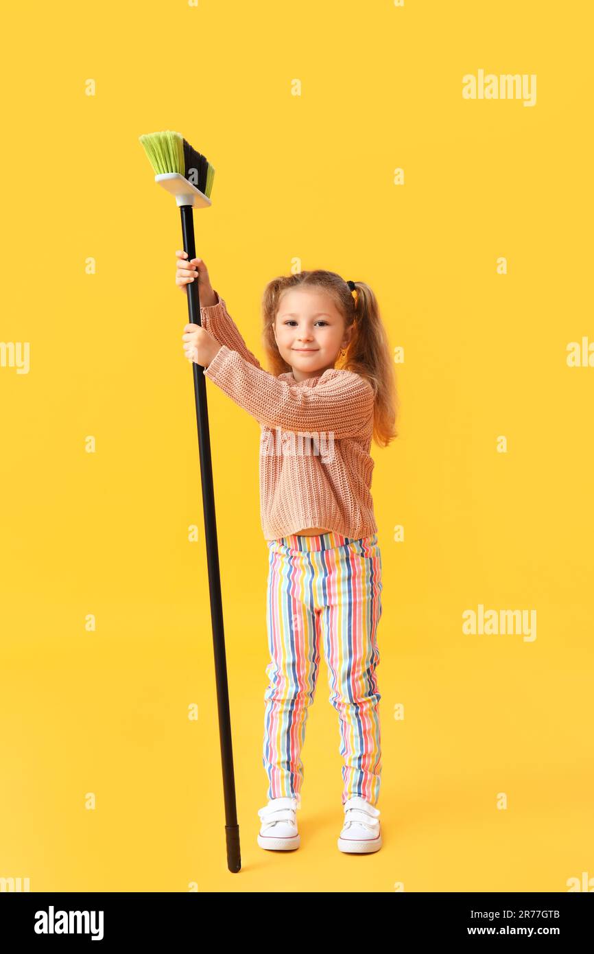 Cute little girl with broom on yellow background Stock Photo - Alamy