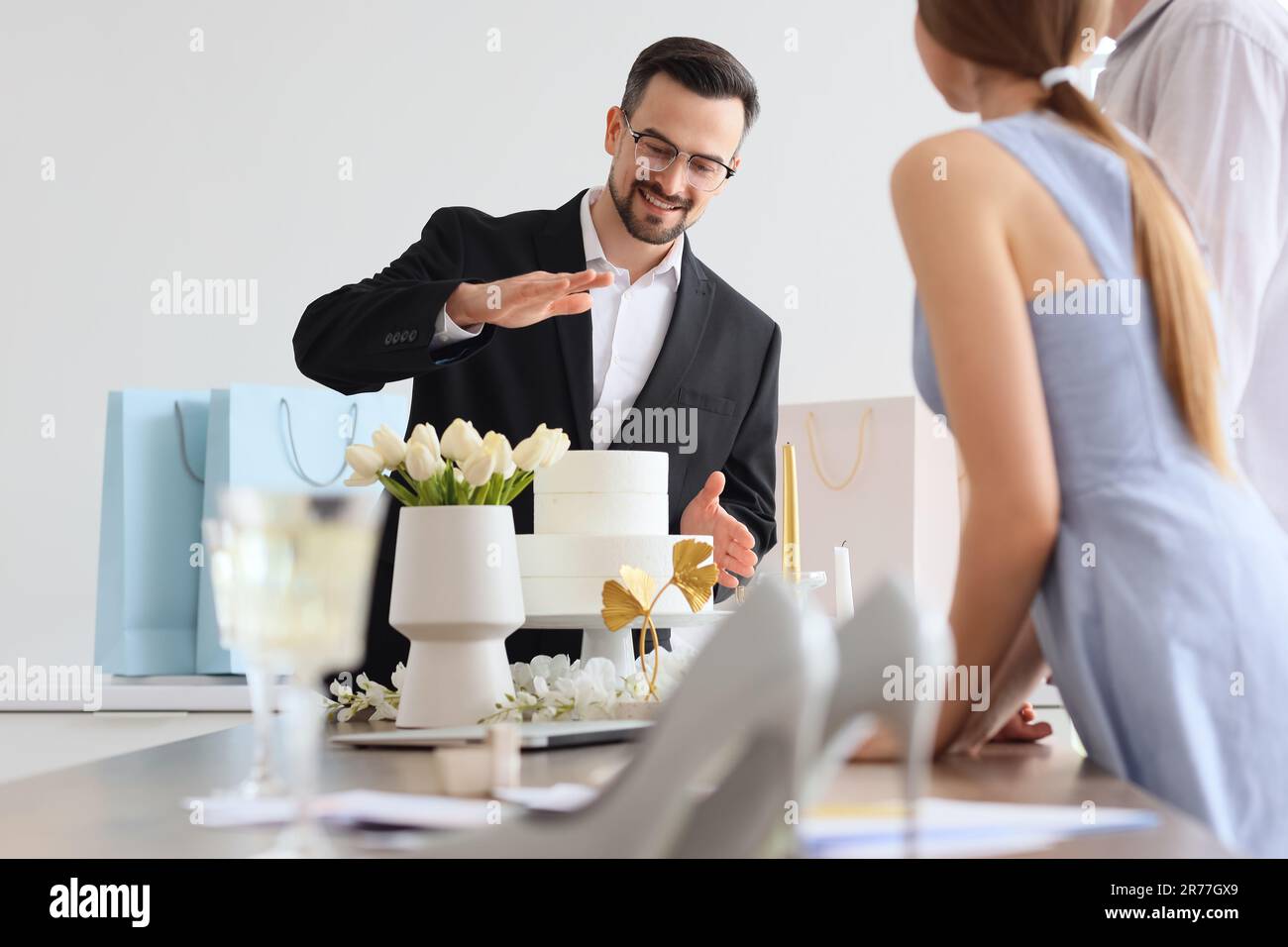Male wedding planner working with couple in office Stock Photo - Alamy