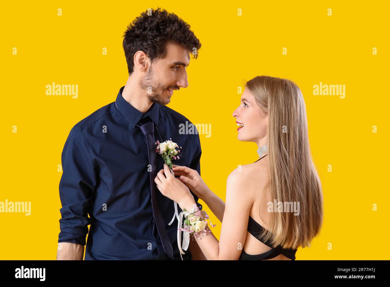 Beautiful prom couple pinning boutonniere on yellow background Stock ...