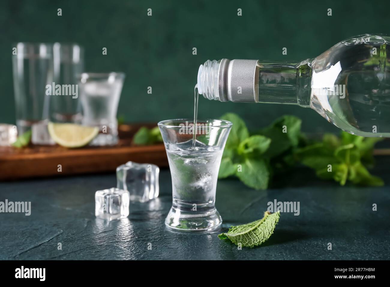 Pouring of vodka from bottle into glass on table Stock Photo - Alamy